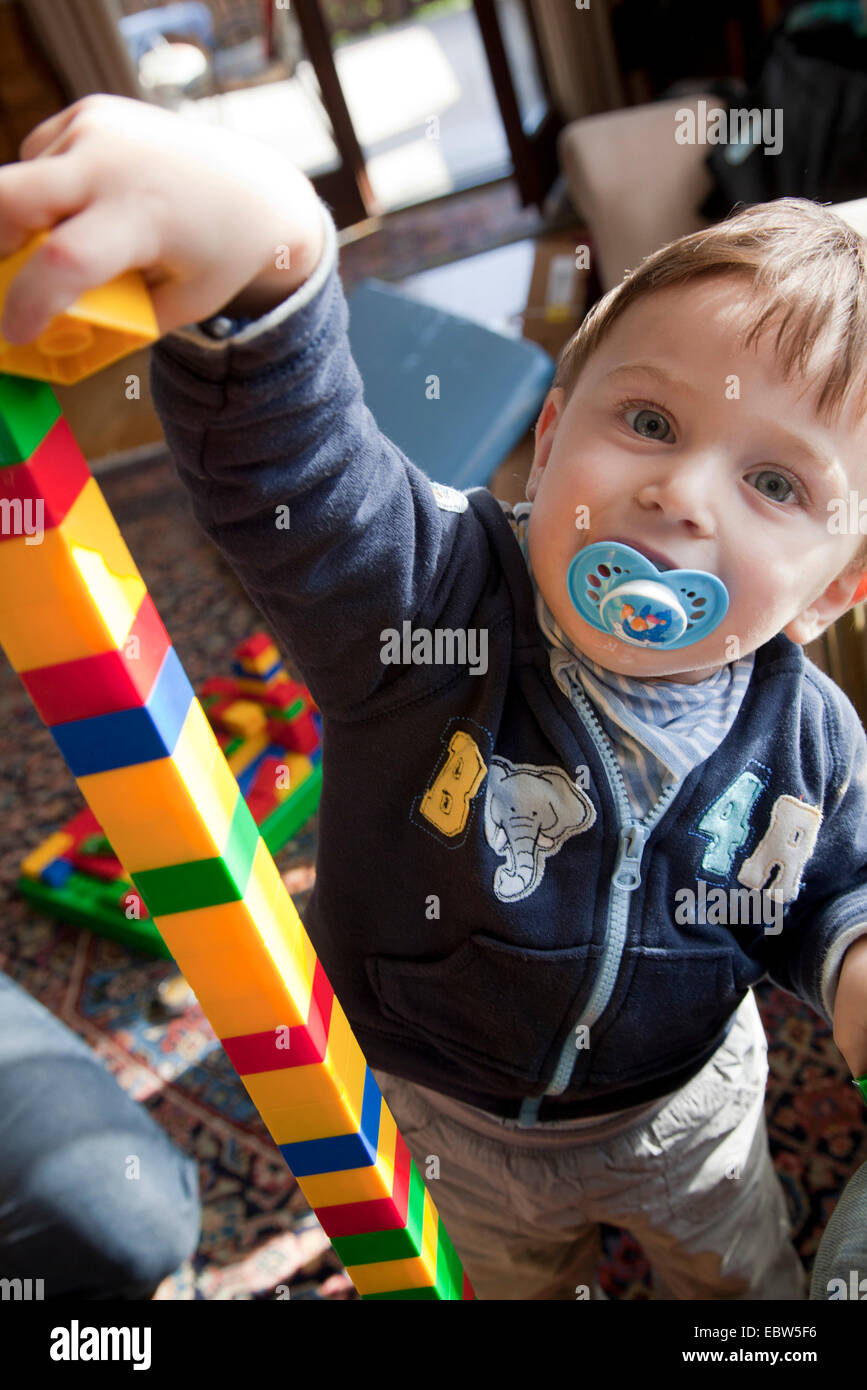 little boy building a LEGO tower that is much higher than he is Stock ...