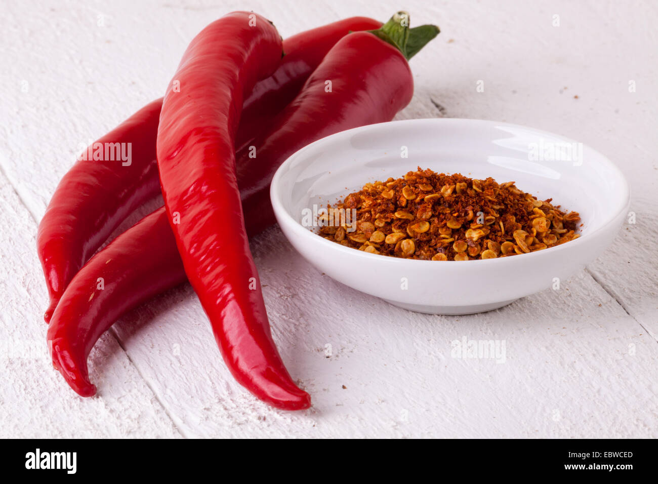Fresh red and yellow chili peppers with a small bowl of dried cayenne ...