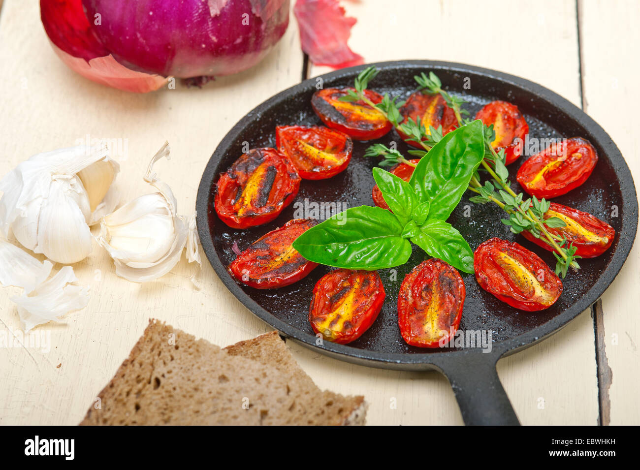 oven baked cherry tomatoes with basil and thyme on a cast iron skillet ...