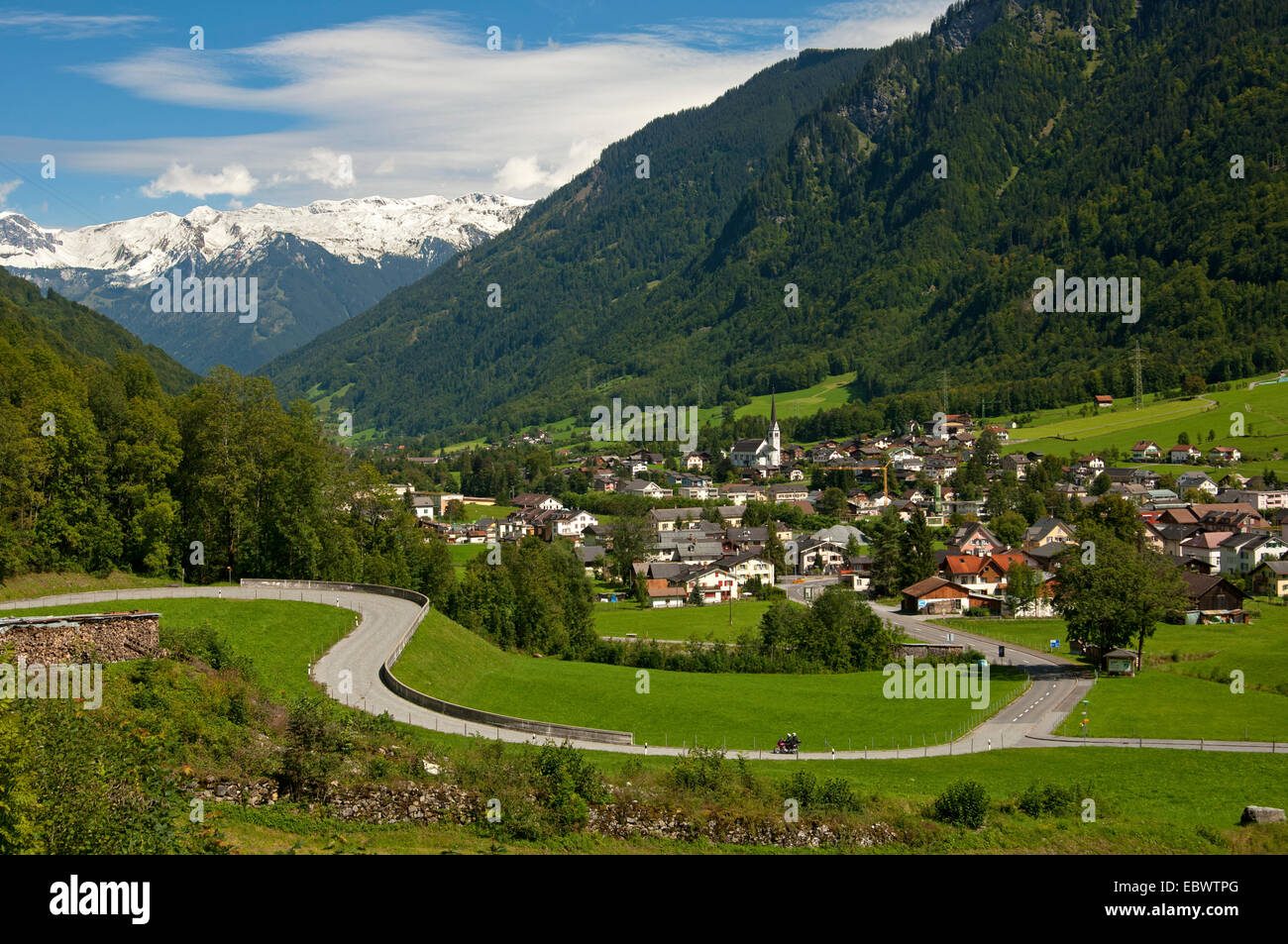 Winding road in front of the village of Linthal, Glarus Alps at back ...
