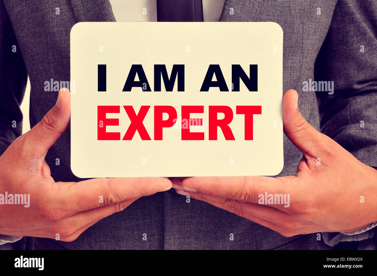 a young man in suit showing a signboard with the text I am an expert ...