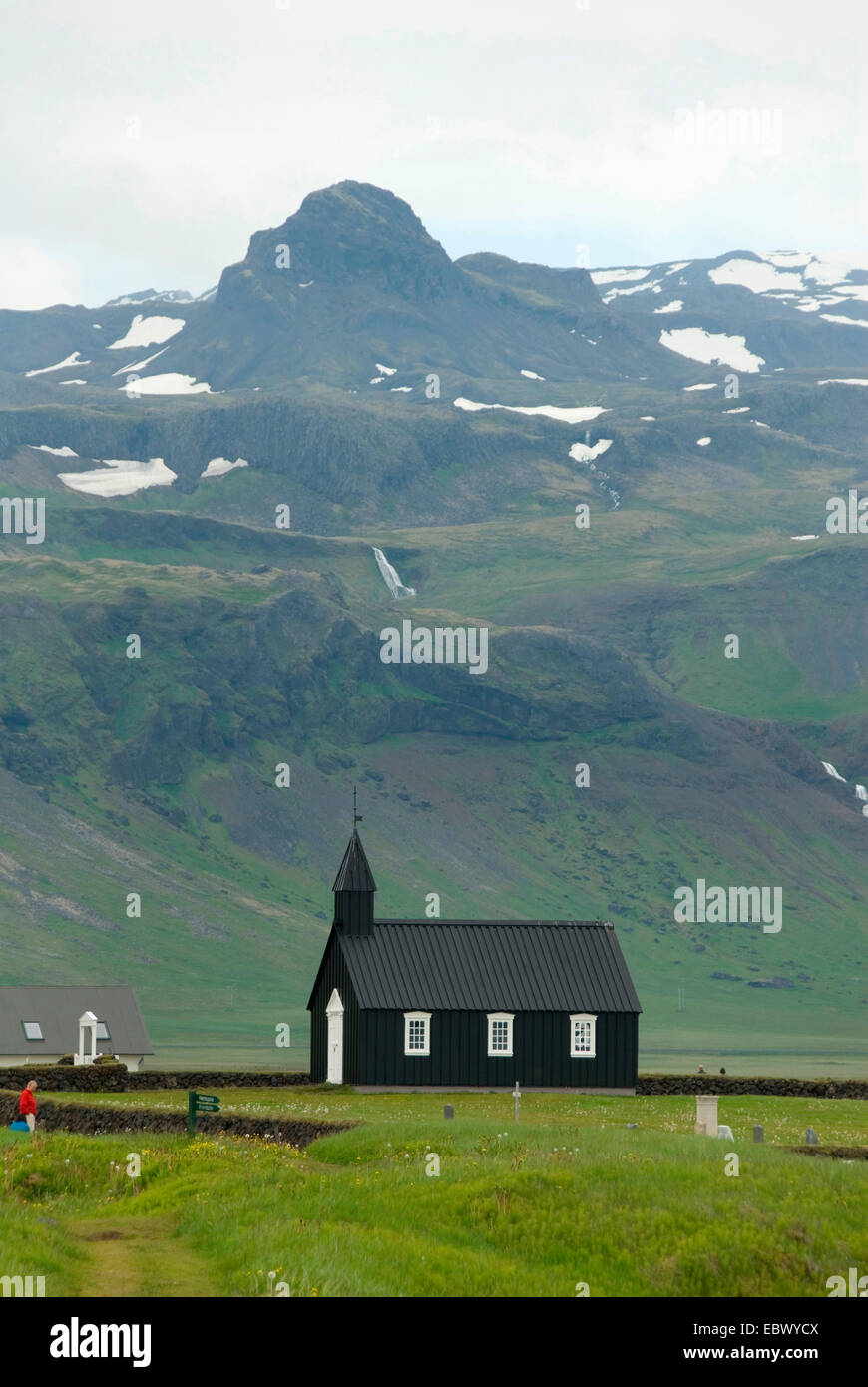 little wooden church 'Budirkirkja' in front of looming mountains ...