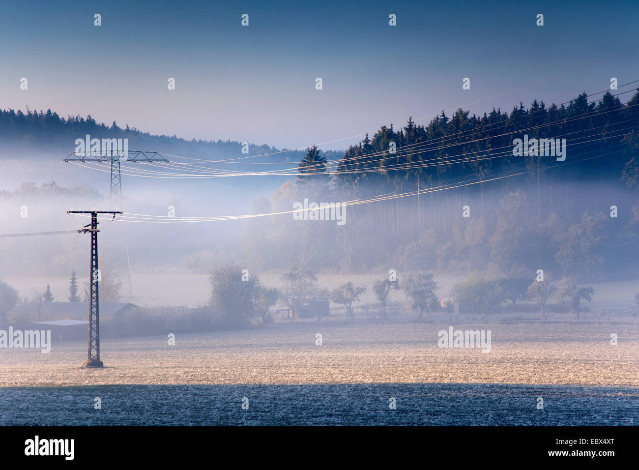 morning mist over field landscape with power pole, Germany, Saxony ...