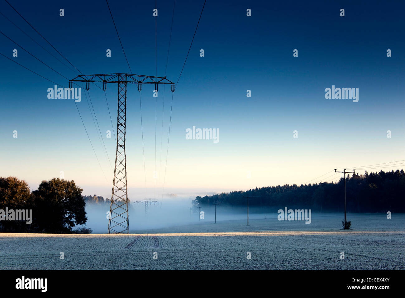 morning mist over field landscape with power pole, Germany, Saxony ...