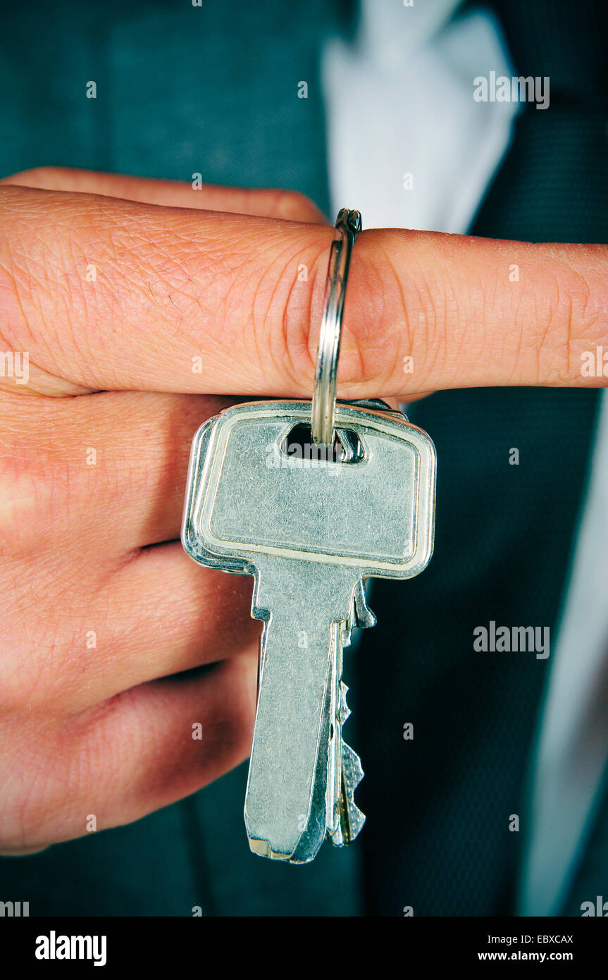 a man wearing a suit with a key ring in his hand Stock Photo - Alamy