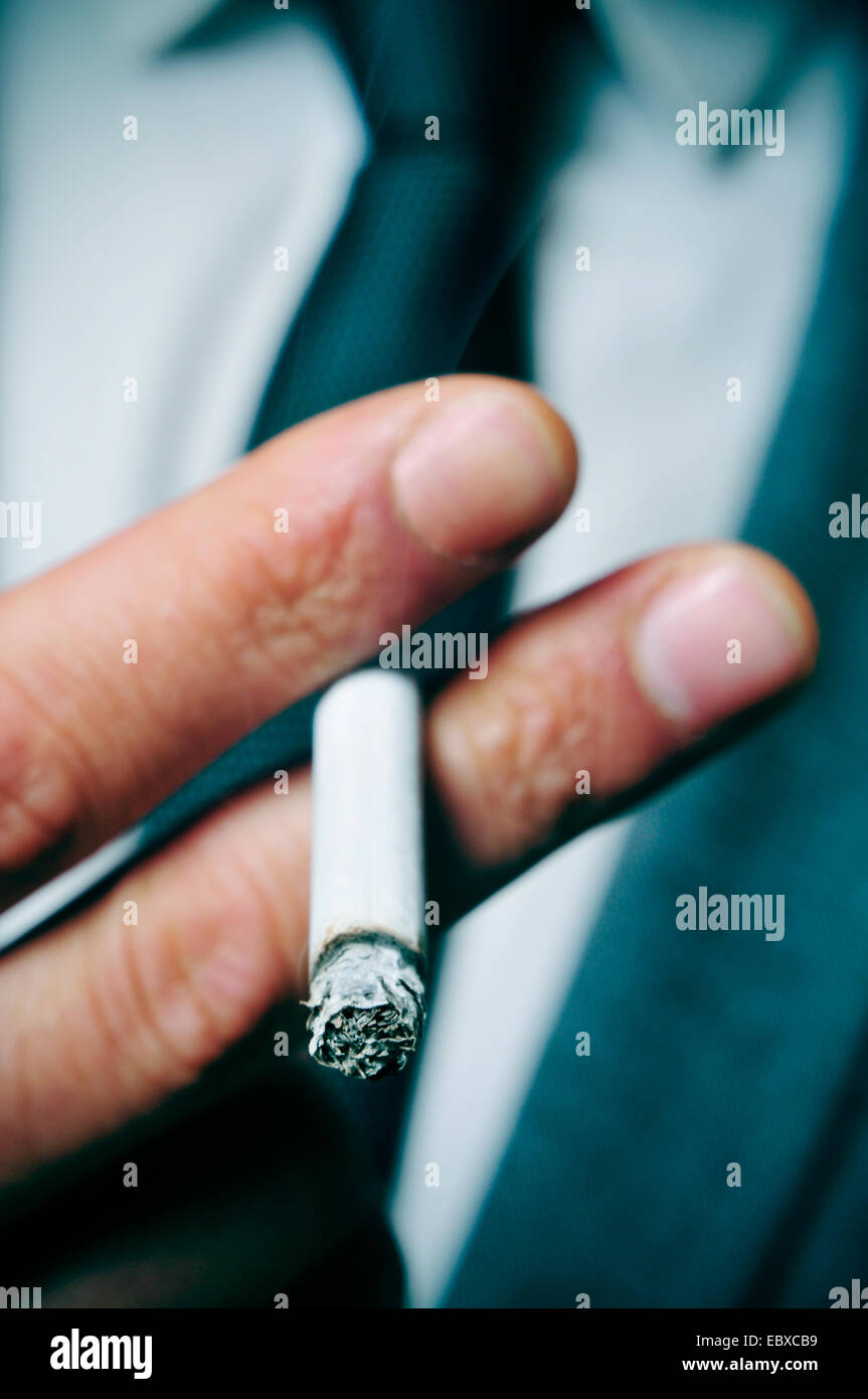 a man wearing a suit smoking a cigarette Stock Photo - Alamy