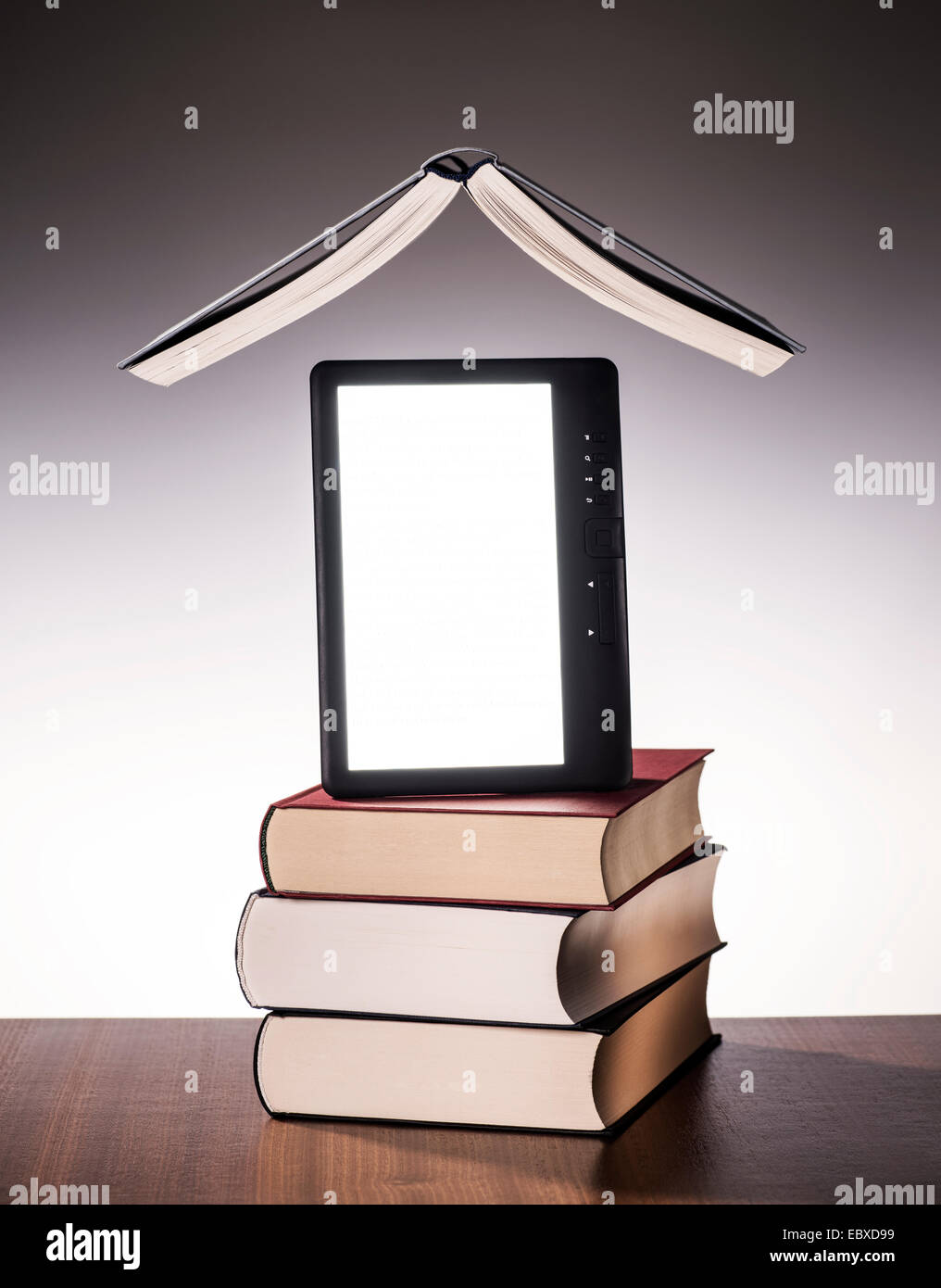 Open book hovering over a stack of printed books and e-book Stock Photo ...