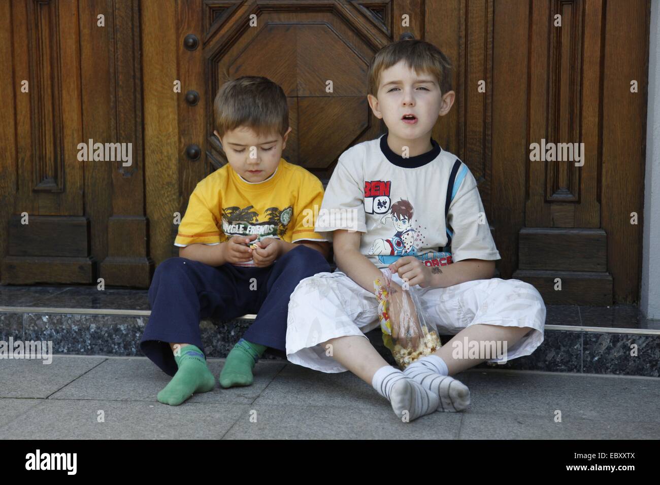 two boys sitting in front of entry door and eating popcorn Stock Photo ...