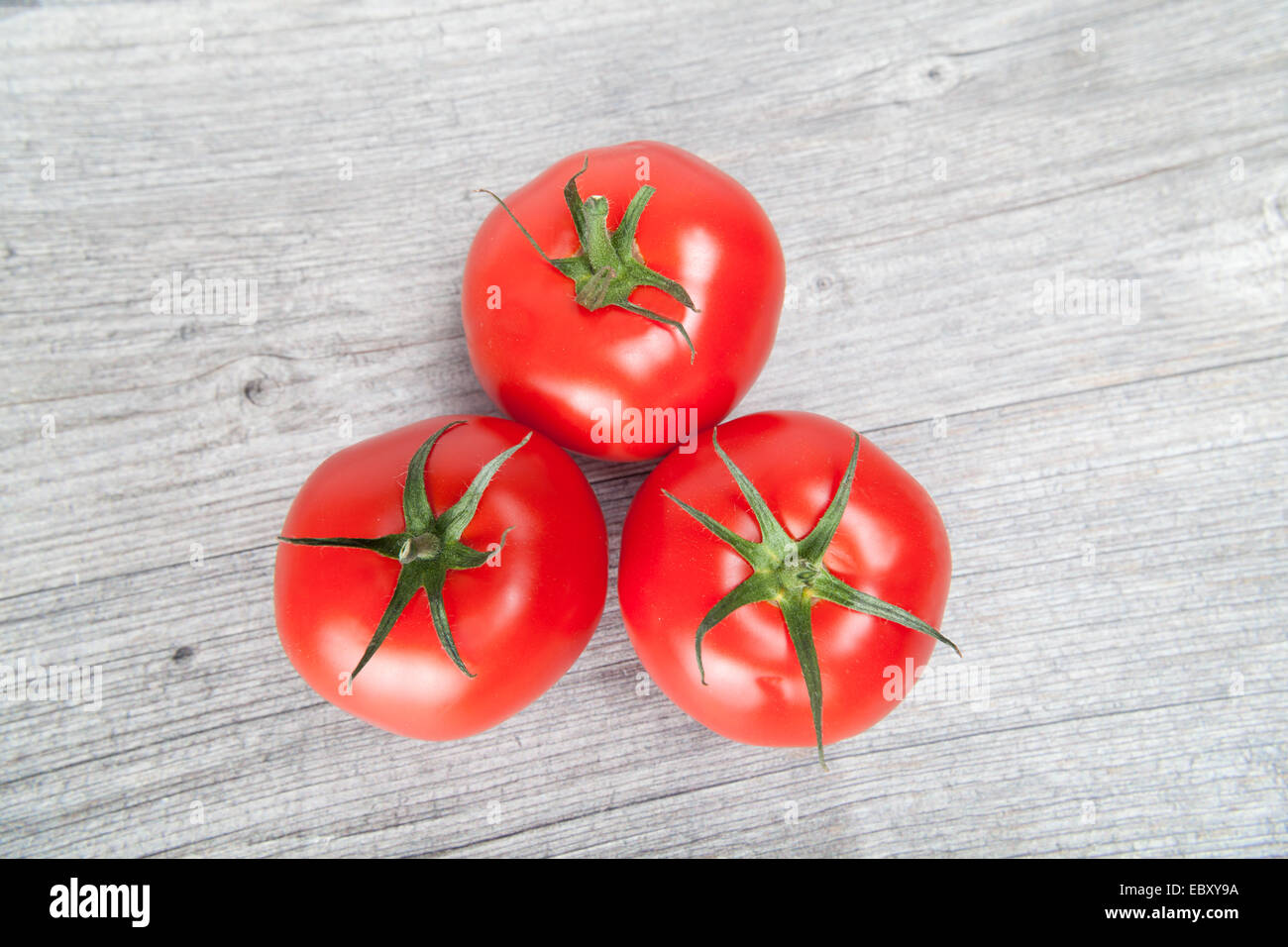 three tomatoes on a grey table Stock Photo - Alamy