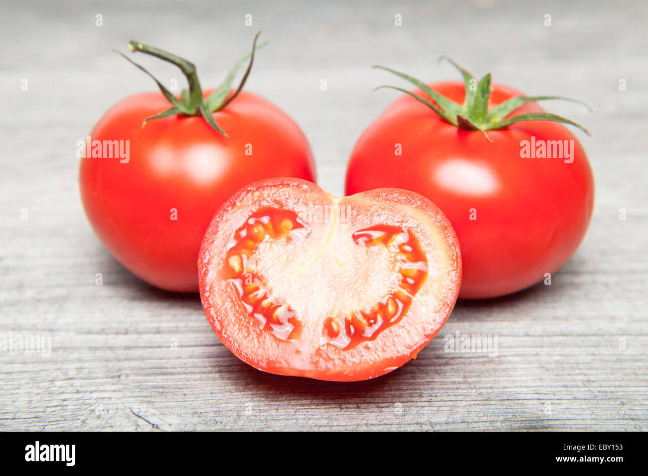 two and a sliced tomate on grey table Stock Photo - Alamy