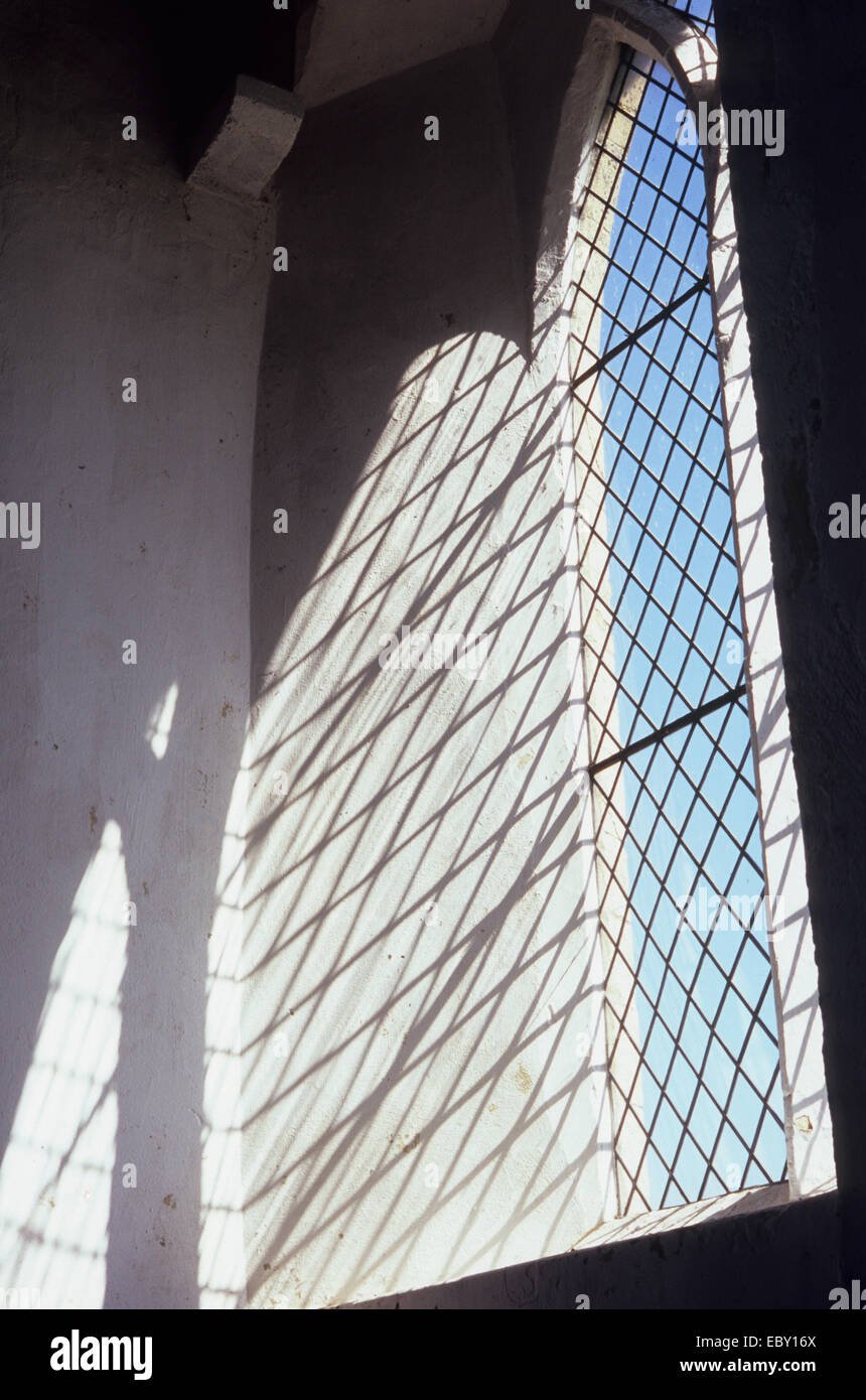 Diamond-leaded Early English plain glass window with clear blue sky ...