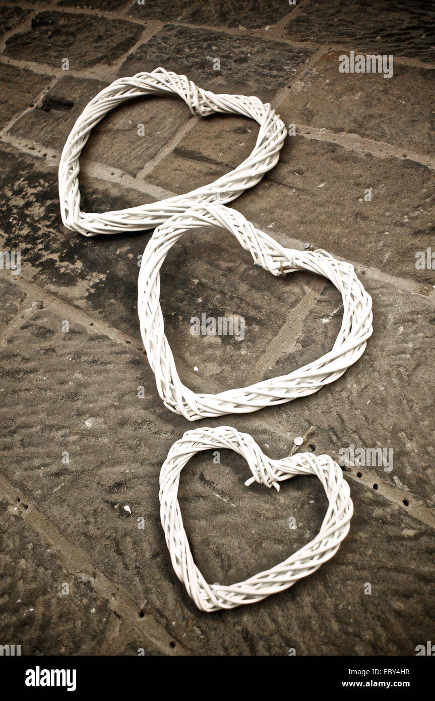 Three vintage wooden wicker hearts on a stone wall background Stock Photo - Alamy