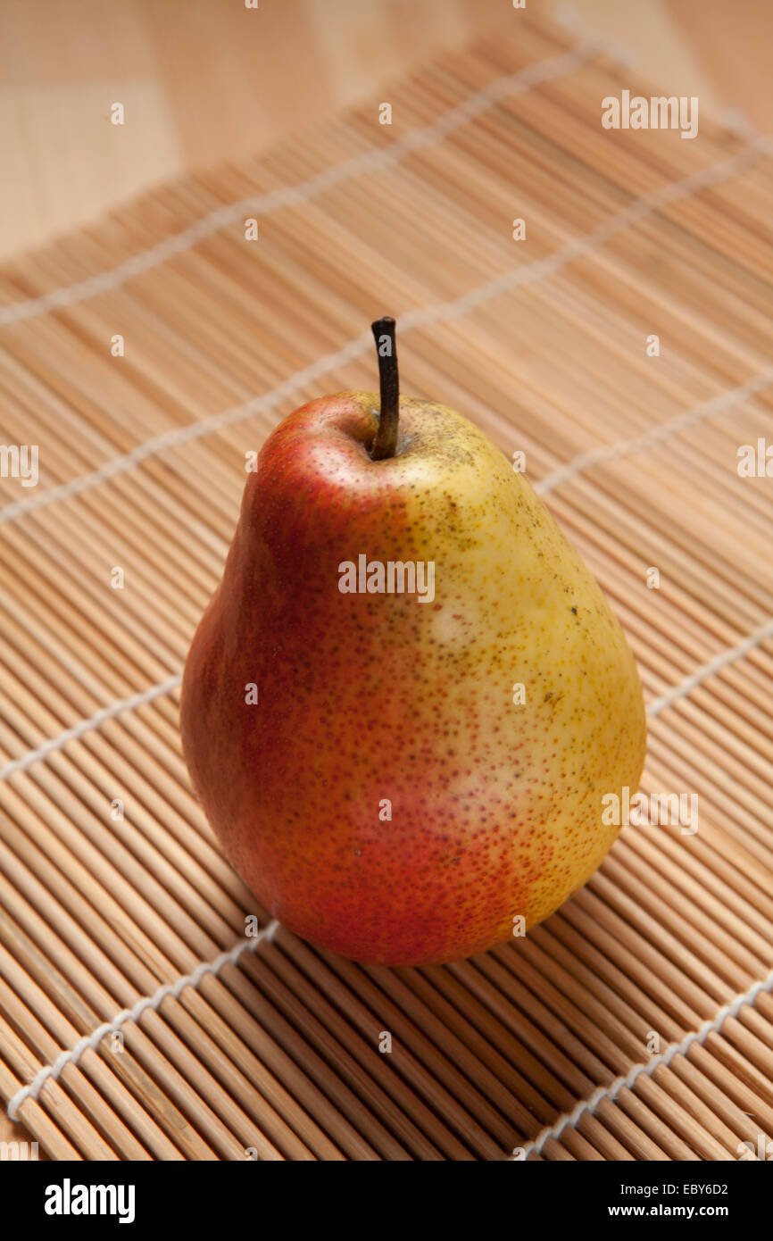A red Anjou pear on a reed mat Stock Photo - Alamy