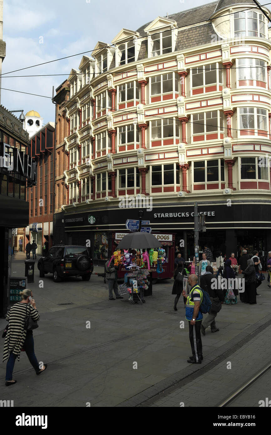 Portrait people crossing Tib Street at Market Street, balloons stall ...