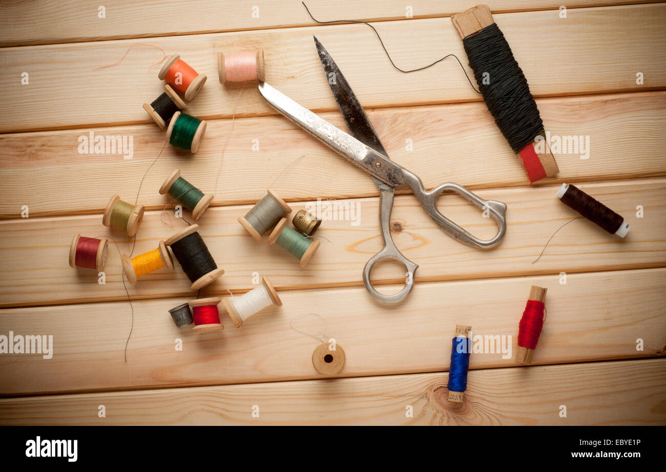 Sewing kit. Scissors, bobbins with thread and needles on the old wooden ...