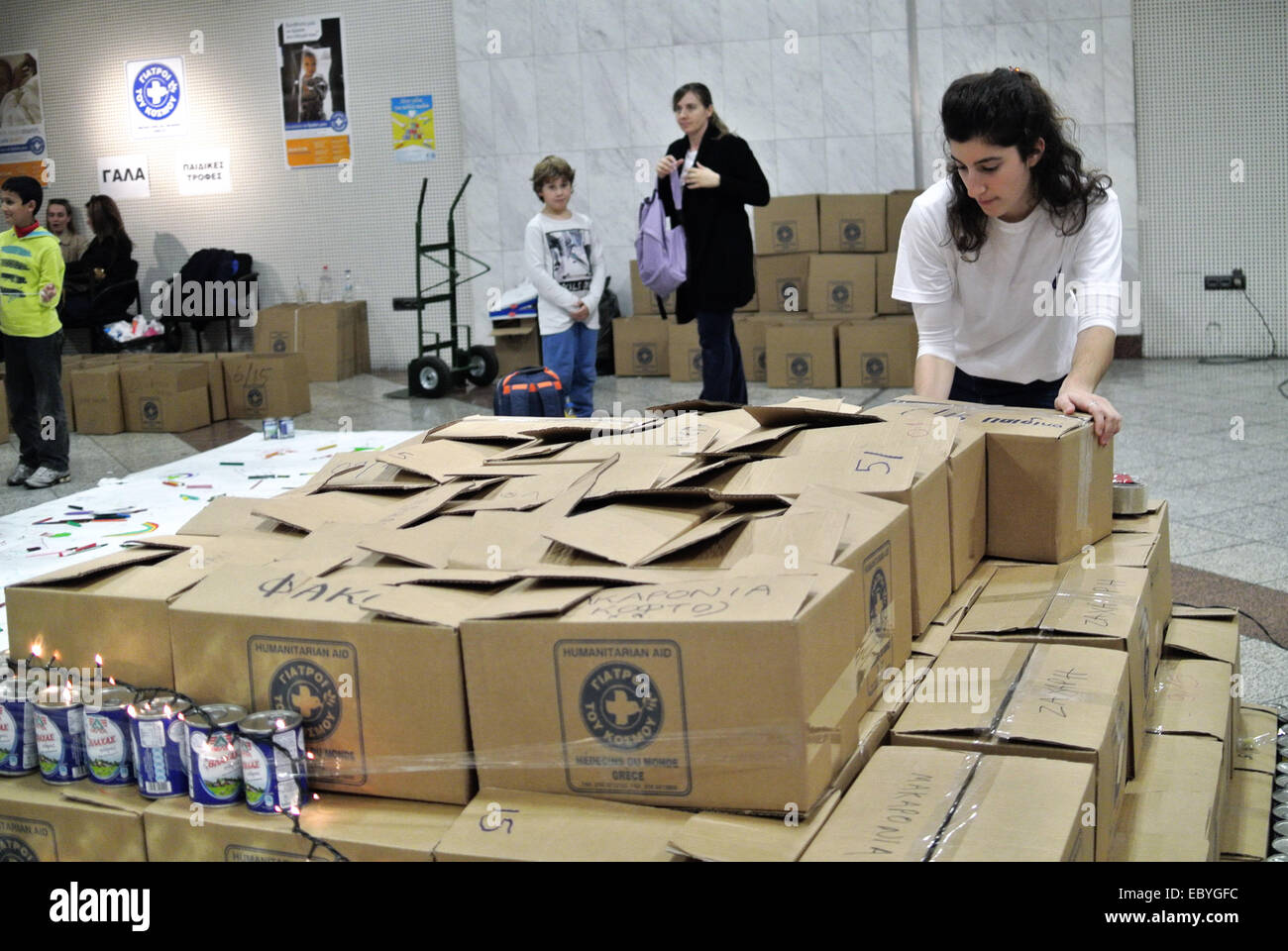 A volunteer helps stack the gathered boxes of milk. The Greek ...