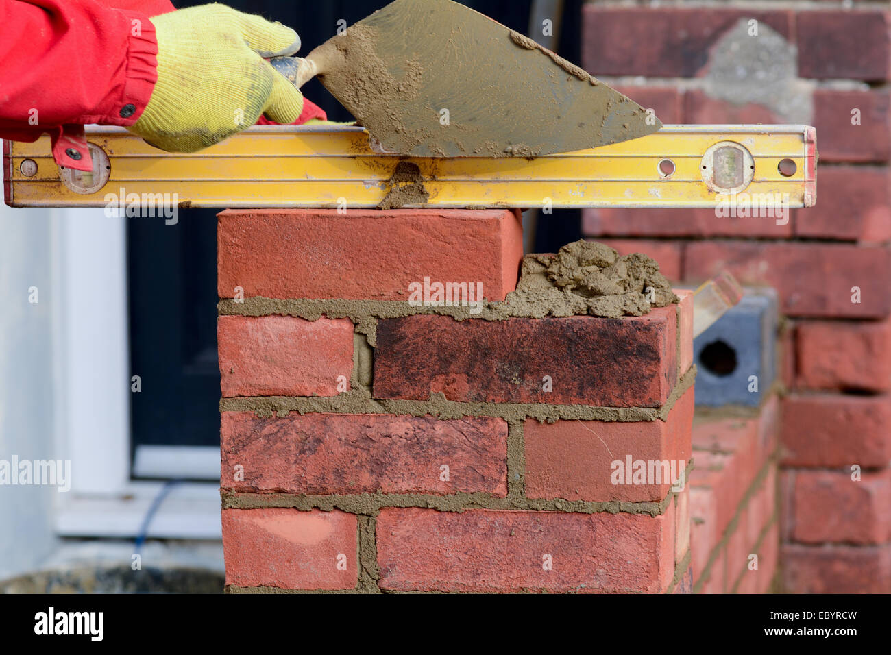 Bricklaying checking brick is level Stock Photo - Alamy