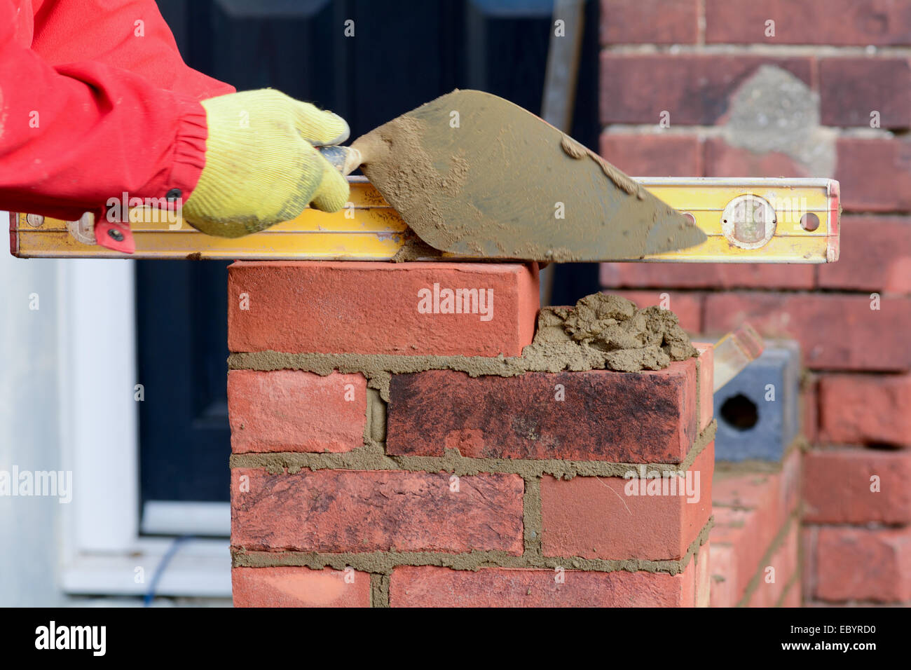 Bricklaying checking brick is level Stock Photo - Alamy