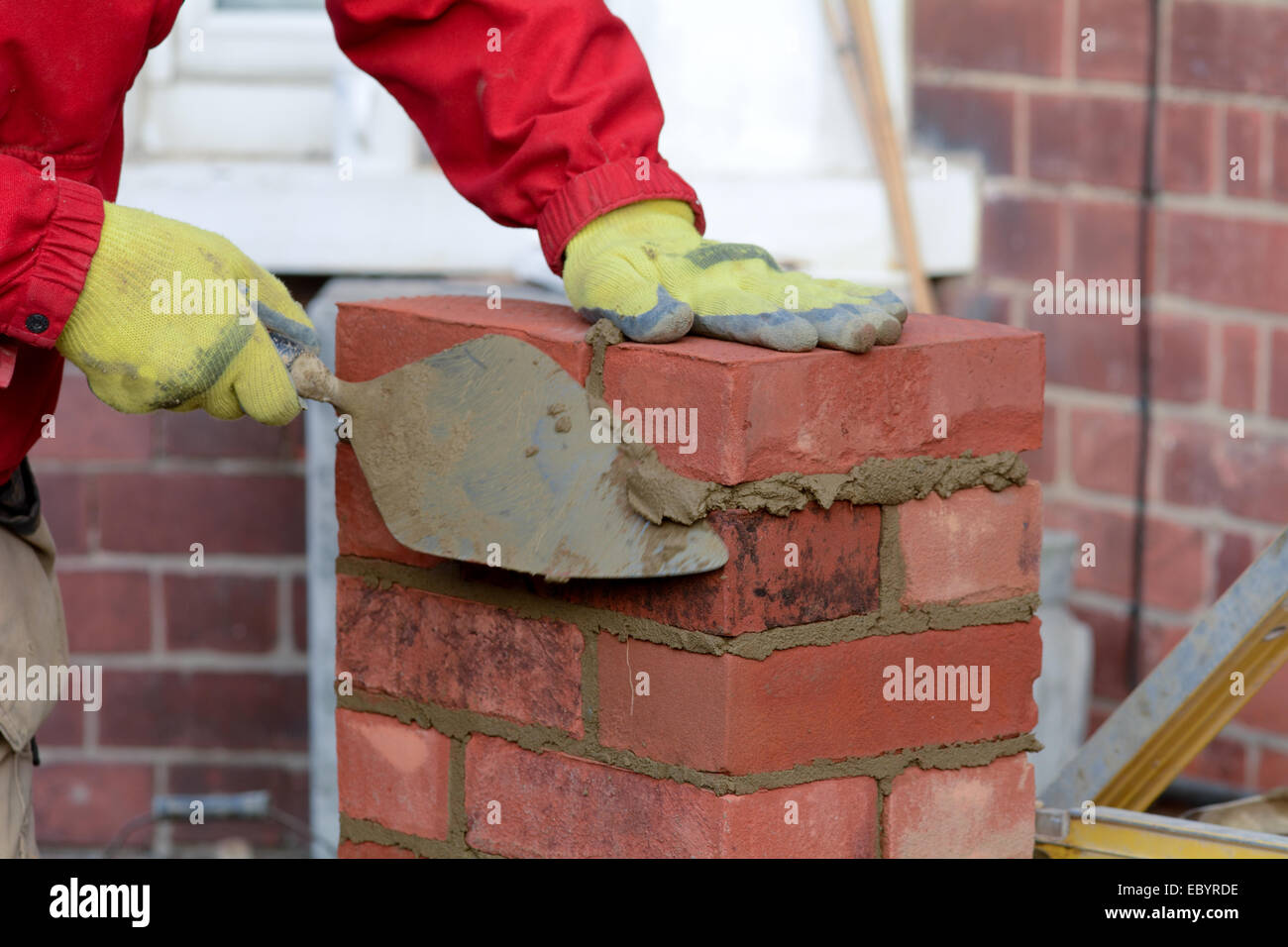 Bricklaying removing excess render next to laid brick Stock Photo - Alamy