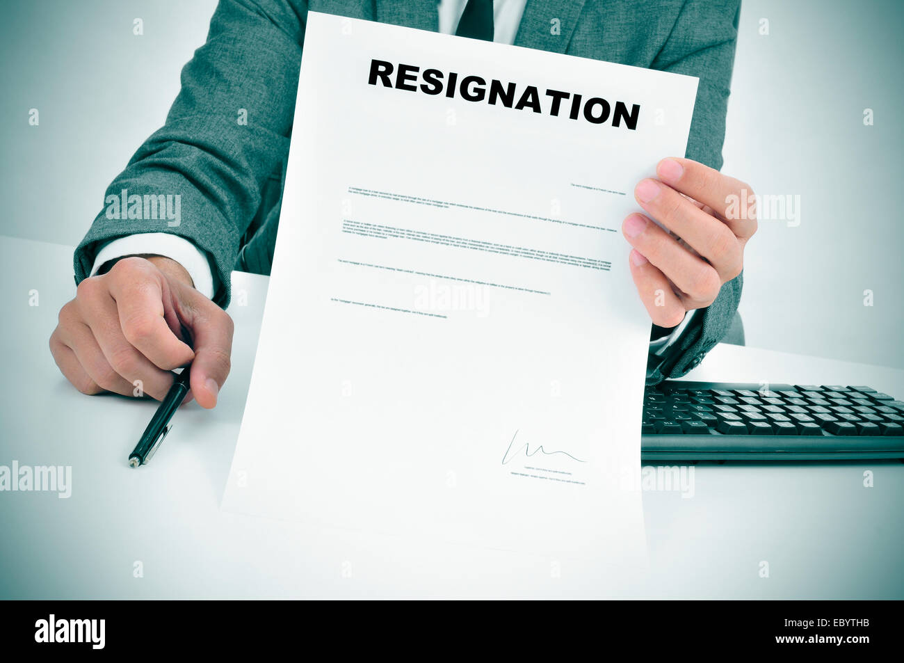 a man in suit in his desk showing a figured signed resignation document ...