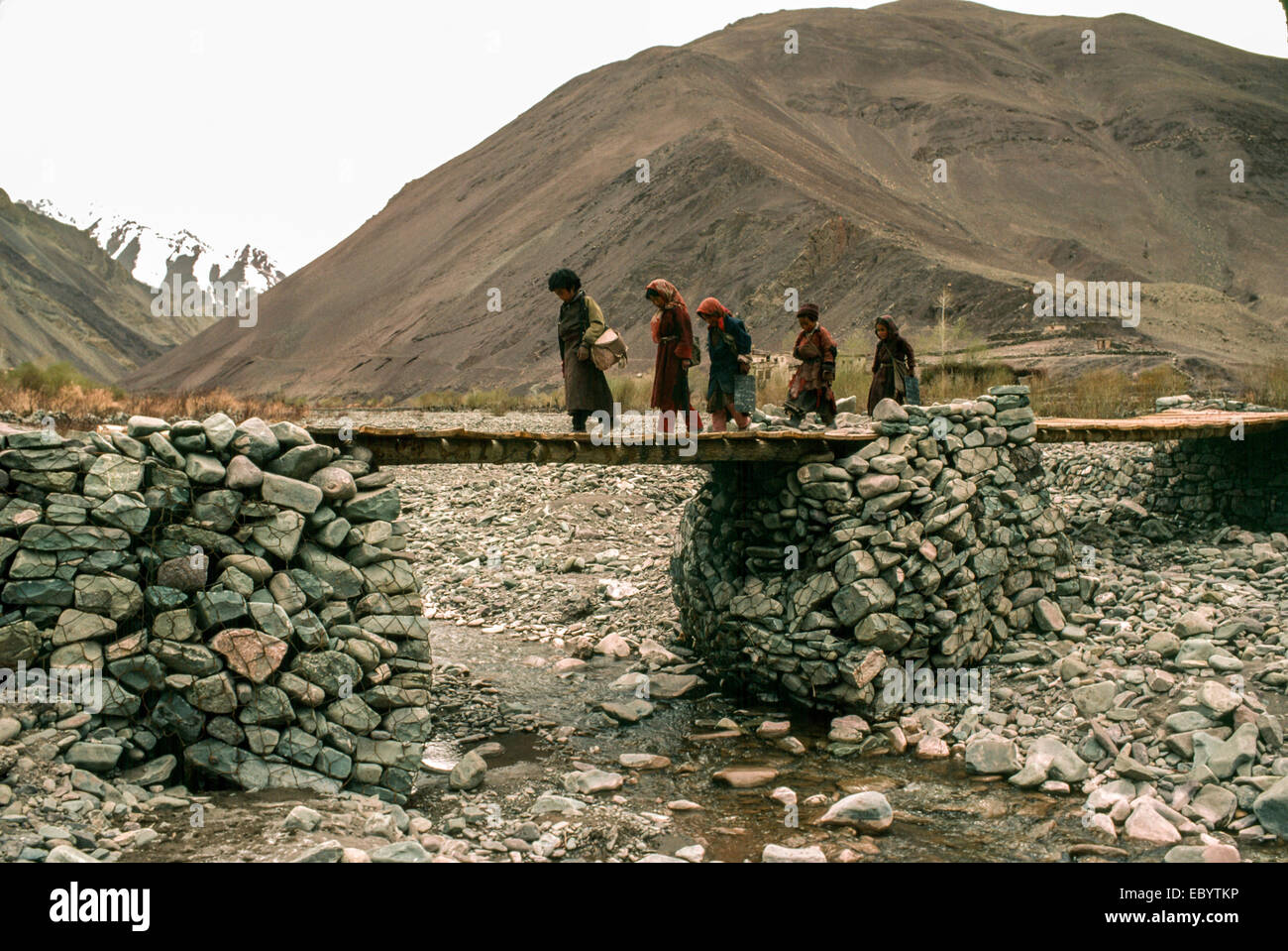 Children walk to school along a flimsy wooden bridge supported by ...