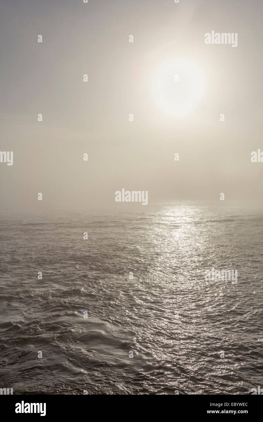 Sun shining through dense fog reflecting on the water Stock Photo - Alamy