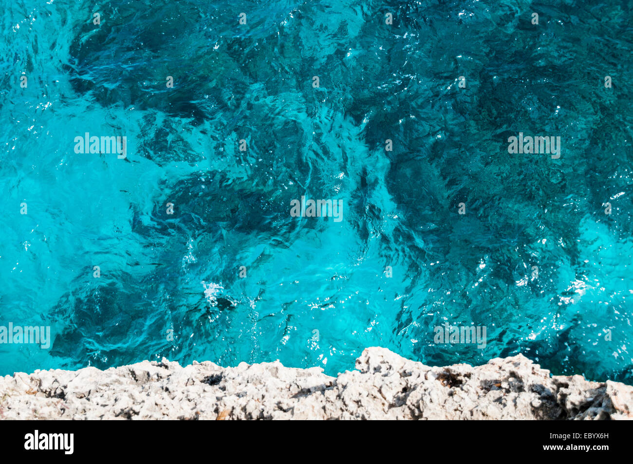 Looking straight over a cliff into the clear blue sea at Calas de ...