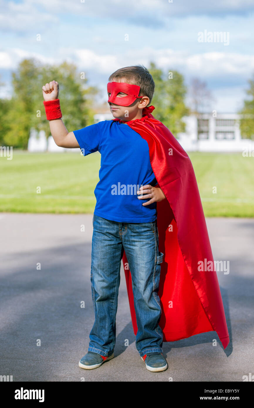 Boy dressed in cape and mask standing with his arm raised Stock Photo ...