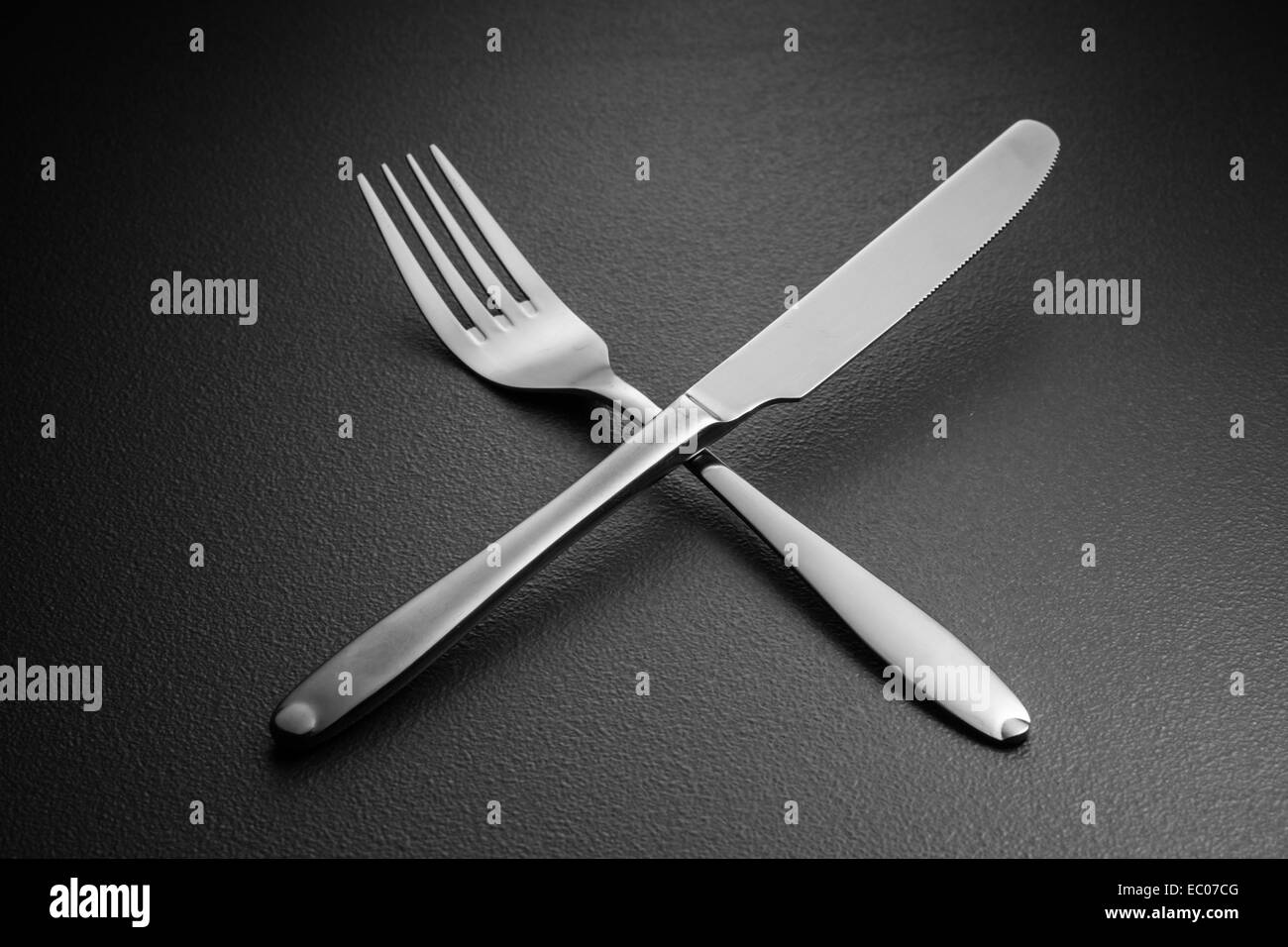 crossed knife and fork on black Stock Photo - Alamy