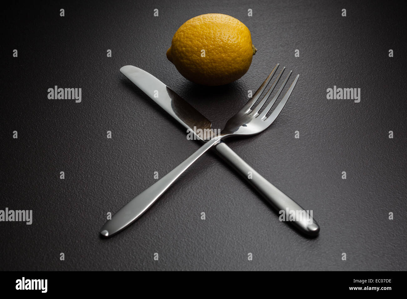 lemon with crossed knife and fork on black Stock Photo - Alamy