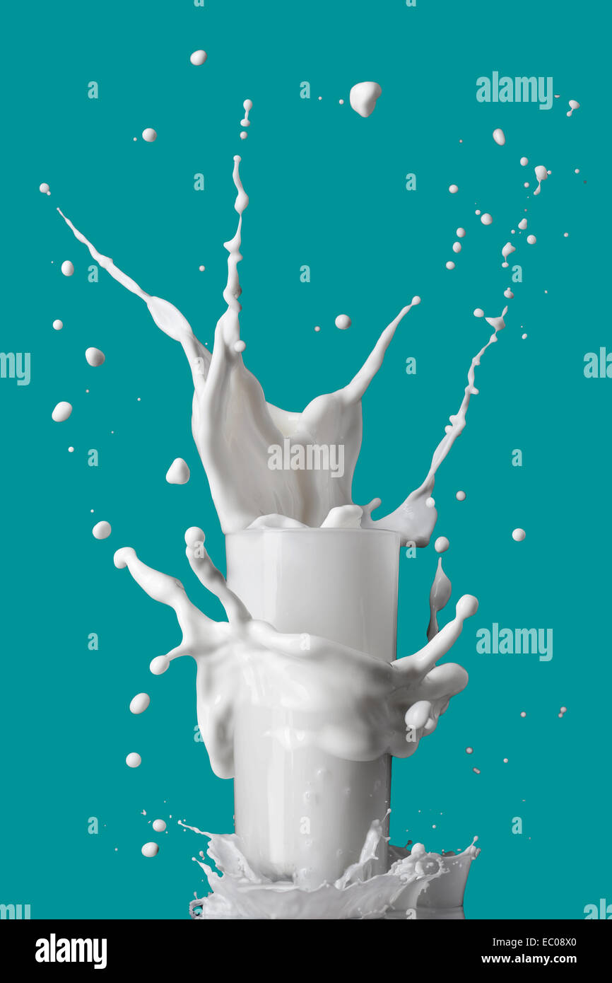 milk splash in glass isolated on blue background Stock Photo - Alamy