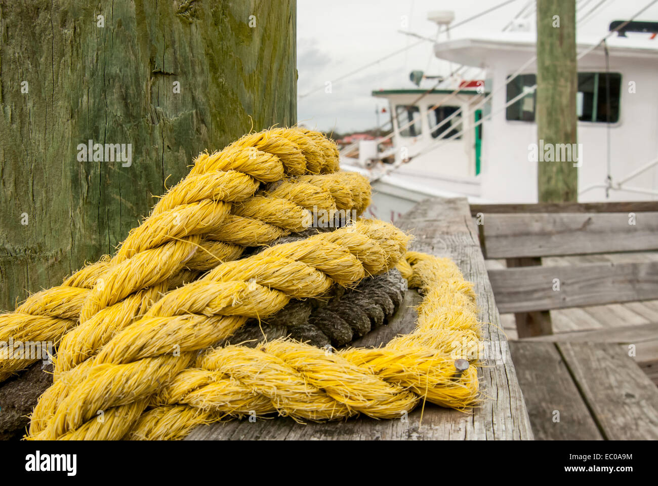 A thick yellow rope is wrapped around a post at a boat dock Stock Photo ...