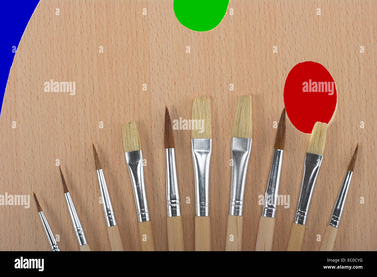 A painter's palette with many different sized brushes and different ...