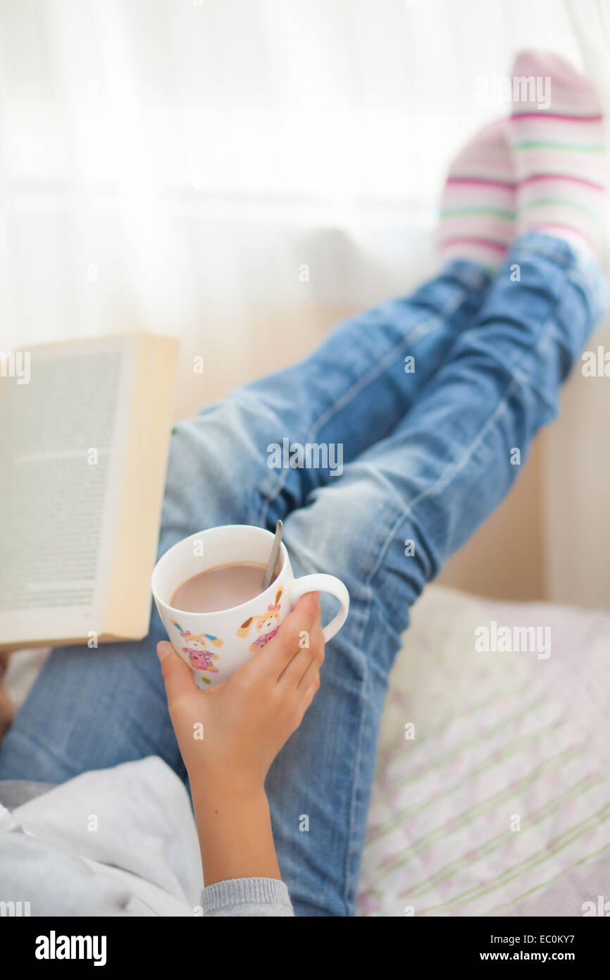 a girl reading a book while eat a wholemeat cookie Stock Photo - Alamy