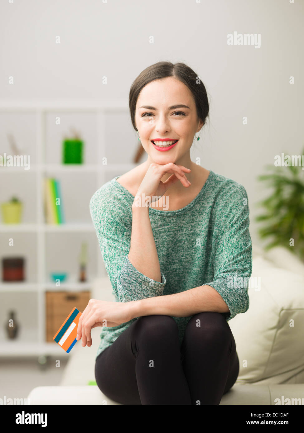 portrait of beautiful young caucasian woman sitting on sofa at home ...