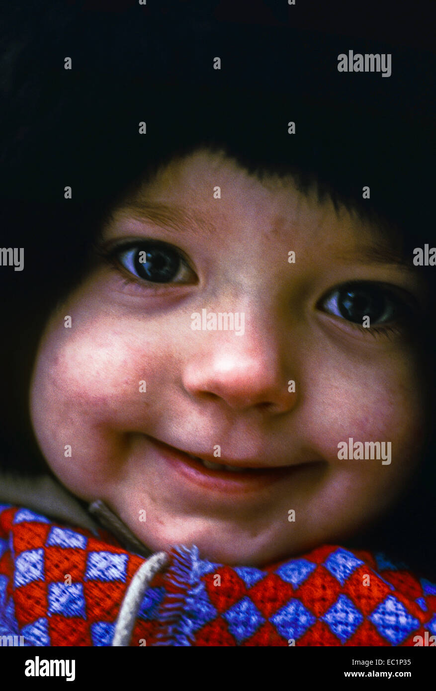 Tiny child in huge fur hat plays in the snow at recess in Kindergarten ...