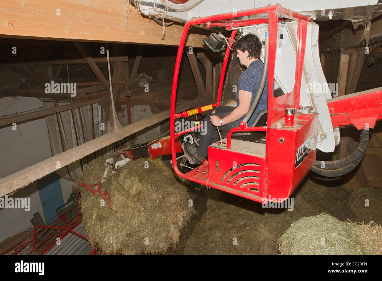 Young farmer using a hay crane, Sprenger family farm, Schwaz District ...
