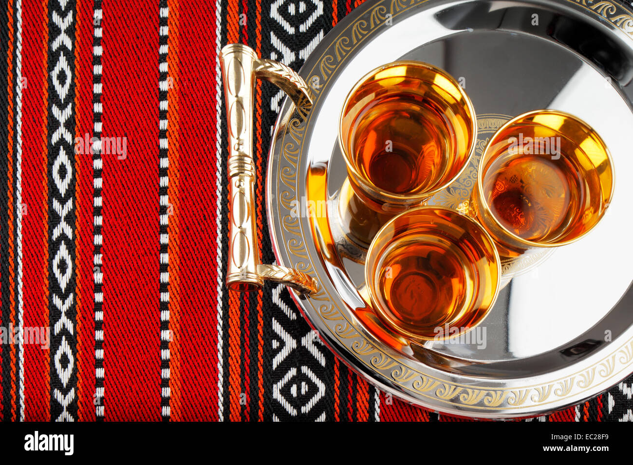 A tray of Arabian tea cups is placed on Arabian woven fabric. Tea ...