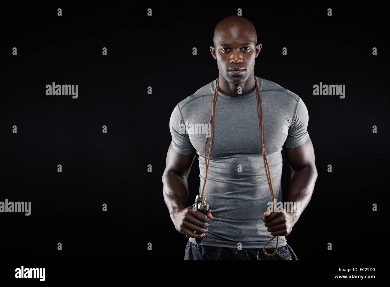 Handsome muscular man posing with jumping rope on black background ...