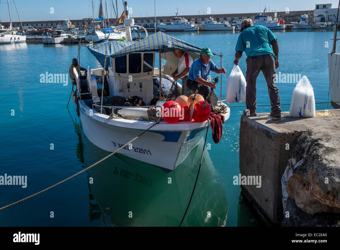 Fisherman loading small fishing boat with fresh supplies before leaving ...