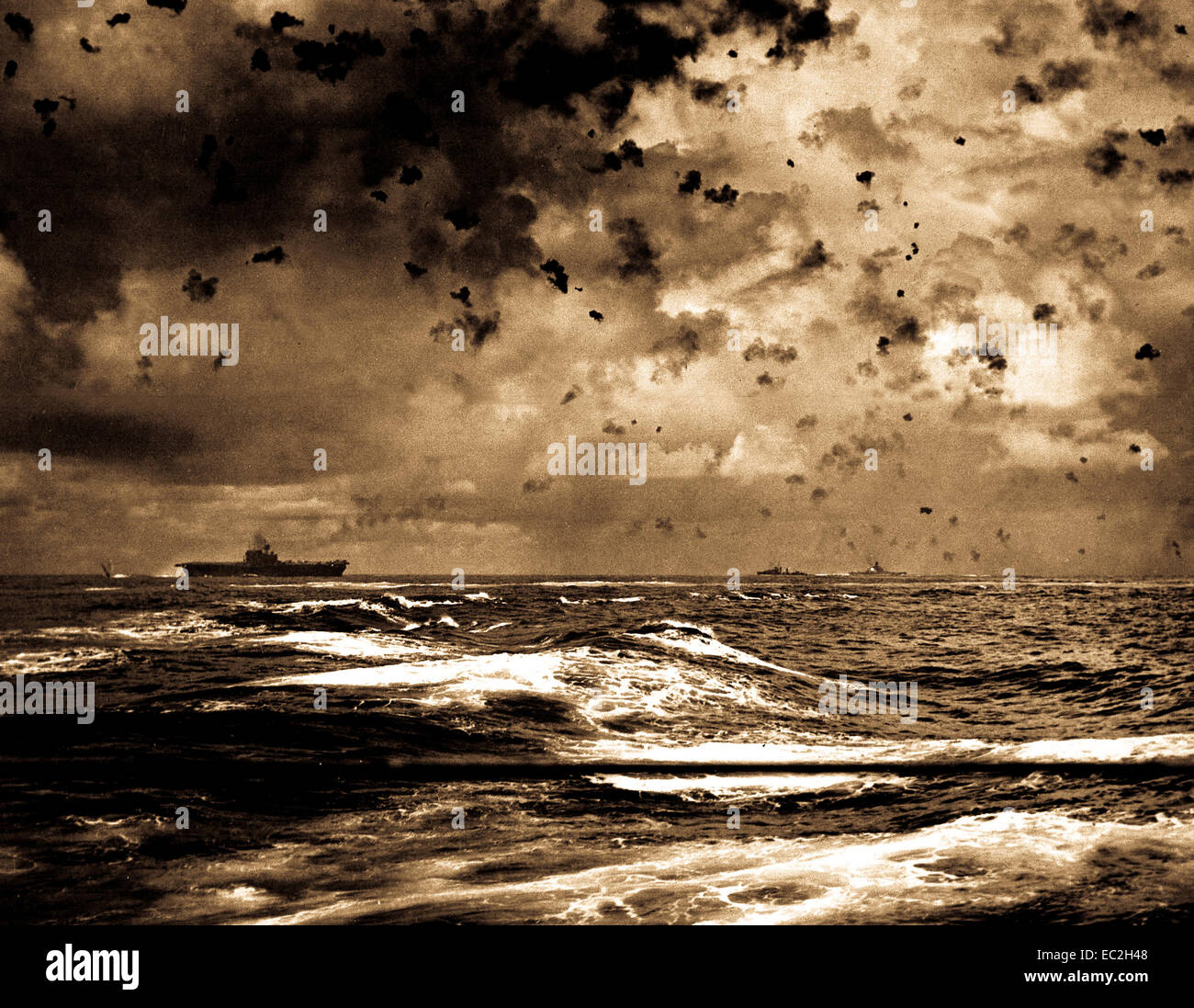 A Japanese bomb splashes astern of a U.S. carrier as the enemy plane ...