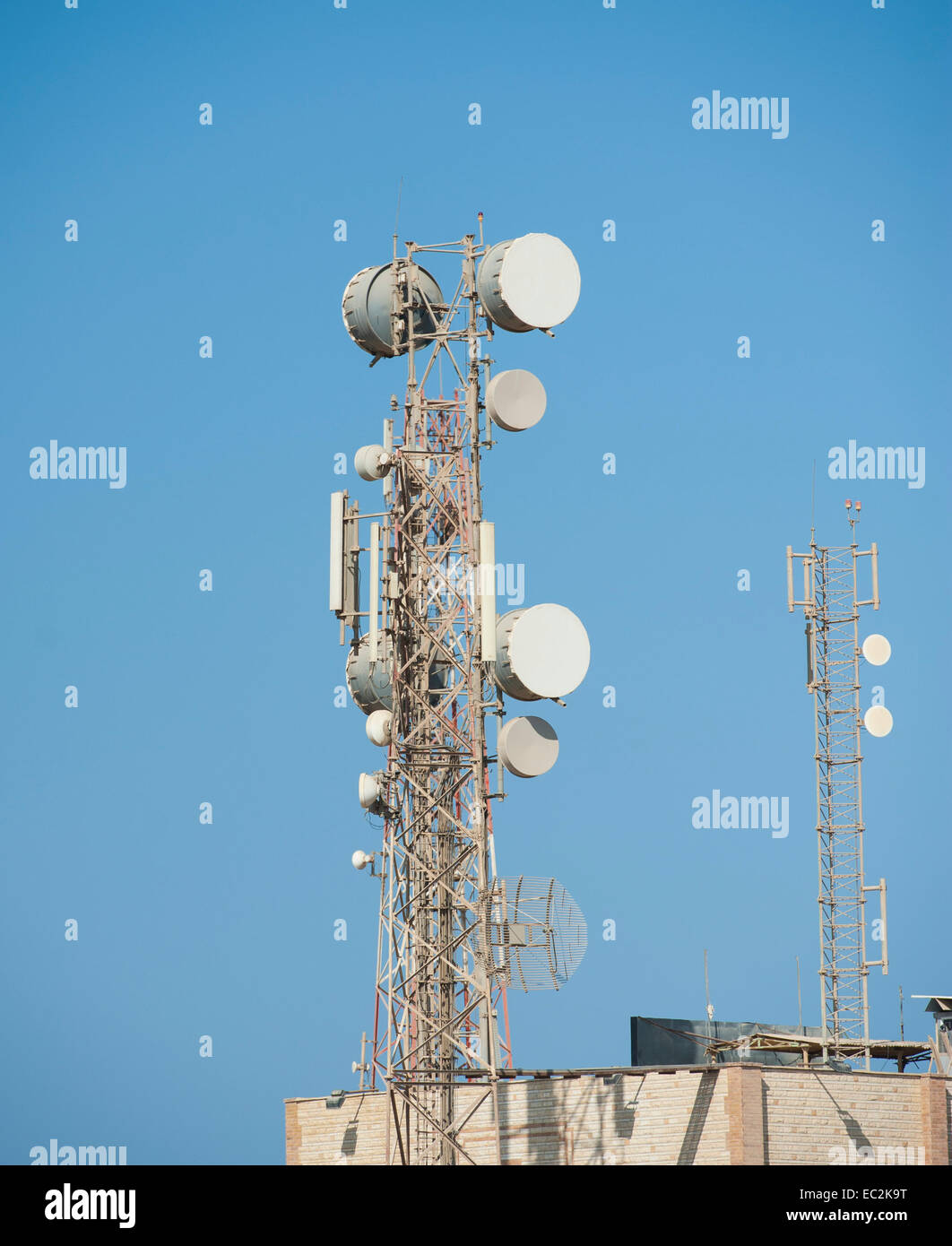 Telecommunications tower pylon against blue sky with satellite dishes ...