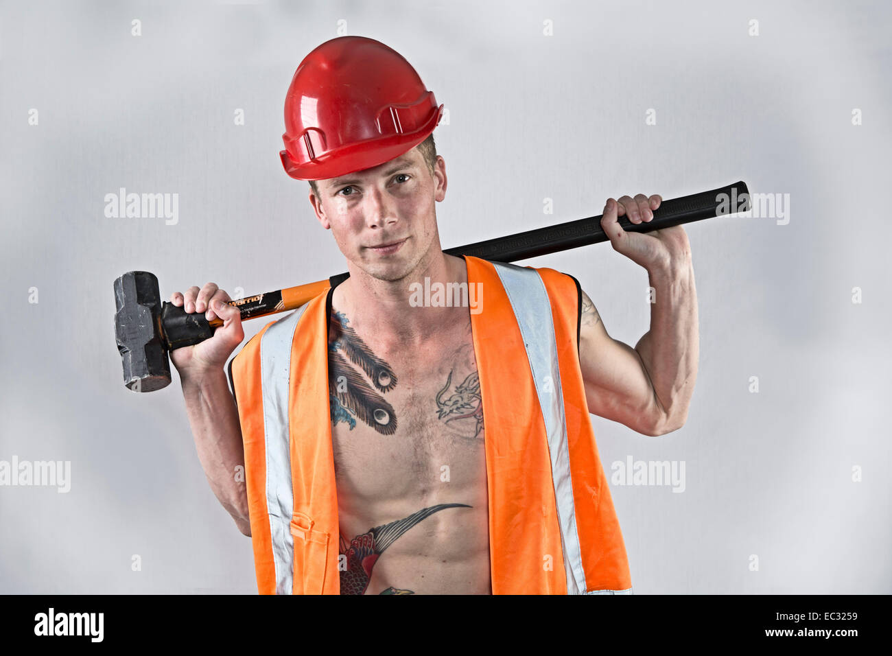 Young fit male shirtless workman with sledge hammer wearing a ...