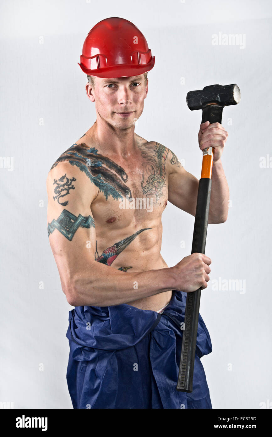 Young fit male shirtless workman with sledge hammer and safety hat ...