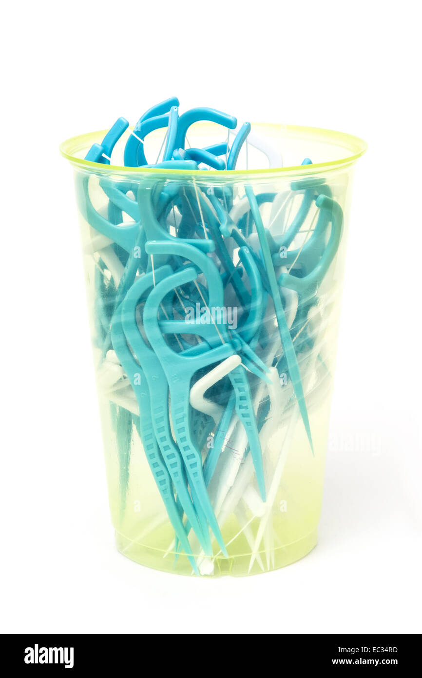 Blue dental floss sticks in plastic cup on a white background. Oral ...