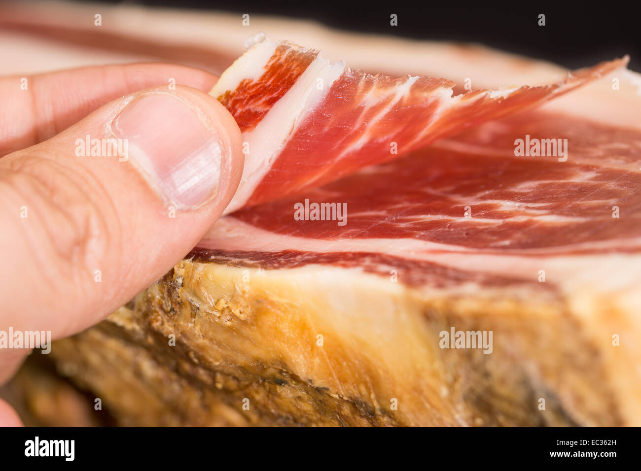 Side view of caucasian man finger taking Serrano ham slice Stock Photo ...