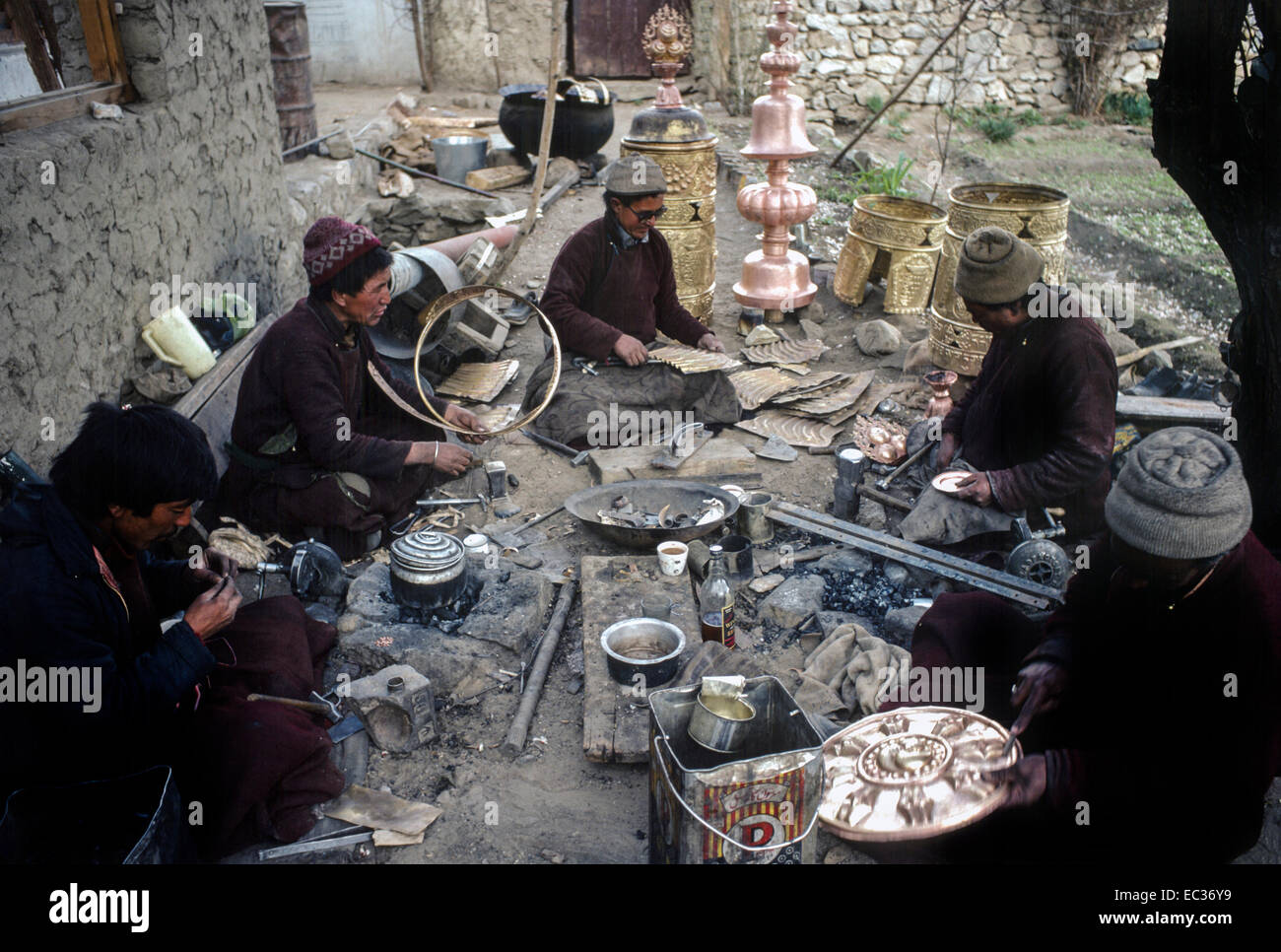 Village brass workers sit outside their workshop making decorative ...