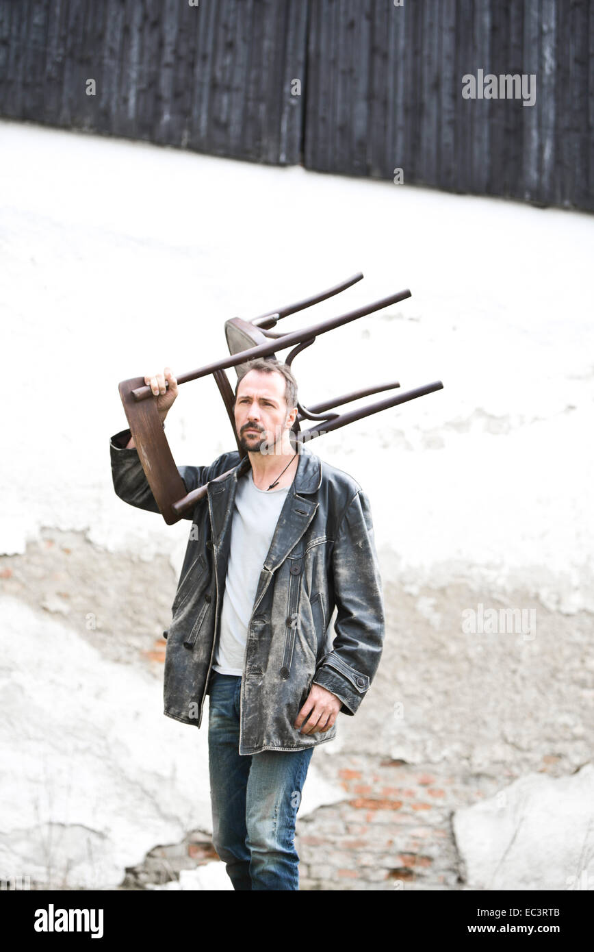 man carries a black chair on his shoulder Stock Photo - Alamy