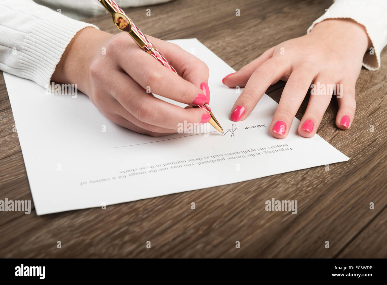 Businesswoman's hand with pen signing a contract Stock Photo - Alamy
