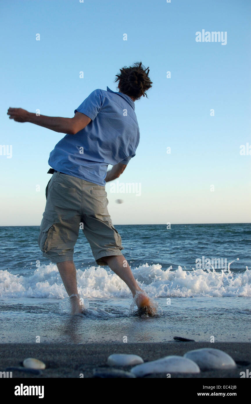 Young Man throwing Stones into Water Stock Photo - Alamy